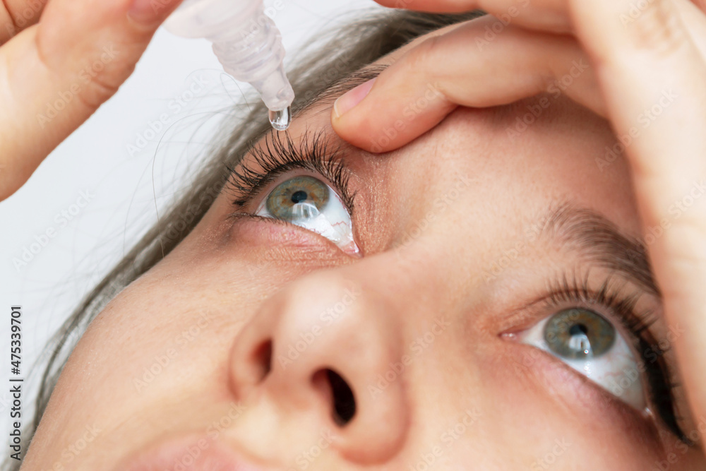 Close-up of woman dripping her eyes with medicinal drops natural tear ...