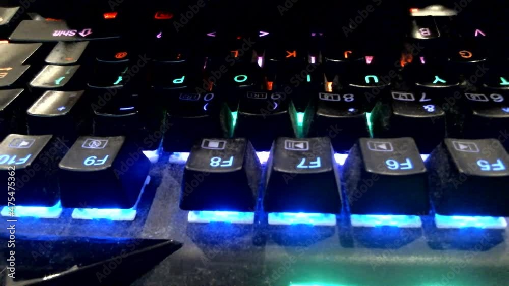 Top down footage of a light-up mechanical keyboard with a gloved person ...