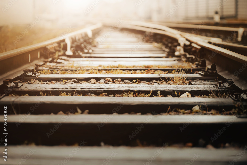 Empty old railway rails with wooden sleepers, illuminated by sunlight ...