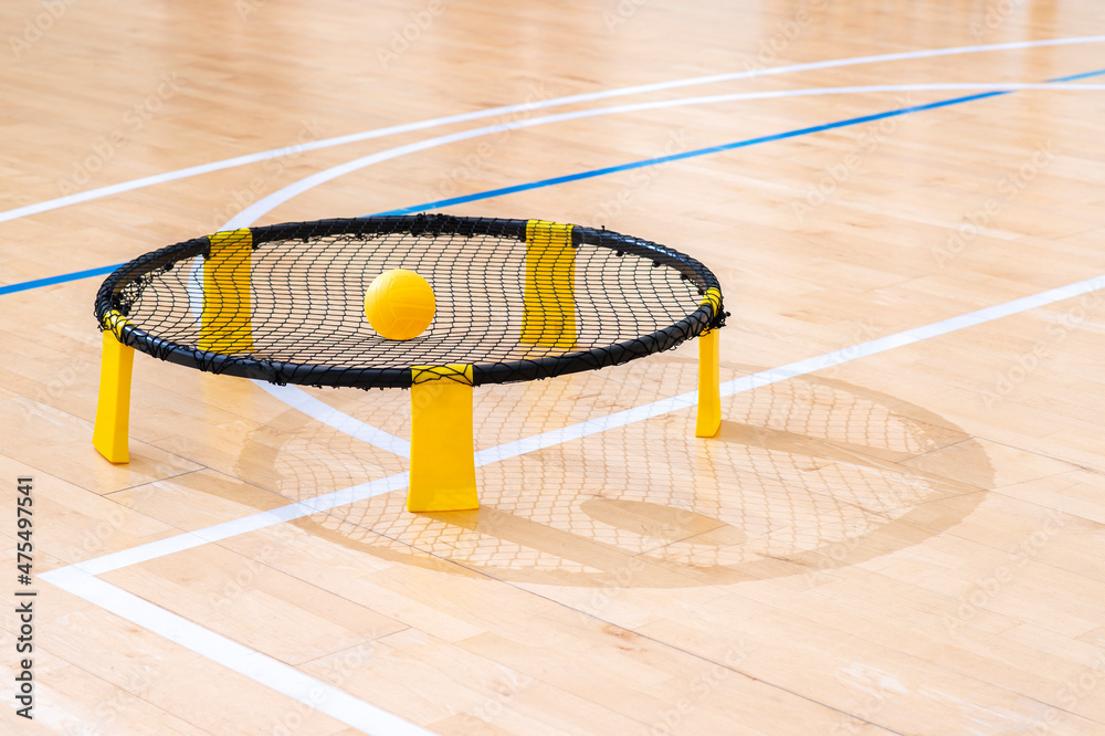 Spike ball game with yellow ball on hardwood court floor. Horizontal ...