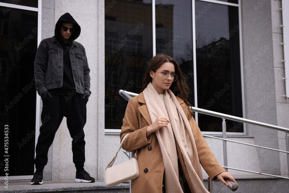 Man stalking young woman near building outdoors Stock Photo | Adobe Stock