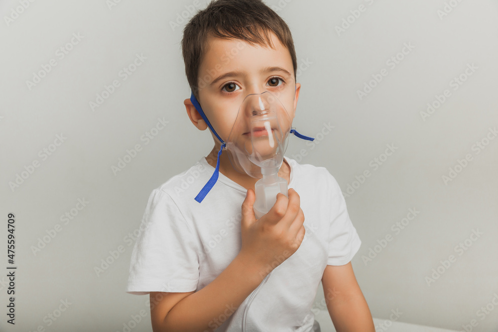 Cute little boy makes inhalation. The child holds an inhaler in his ...