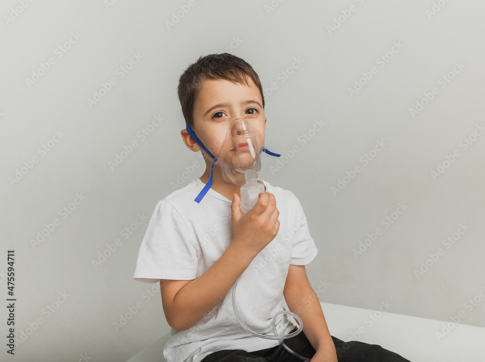 Cute little boy makes inhalation. The child holds an inhaler in his ...