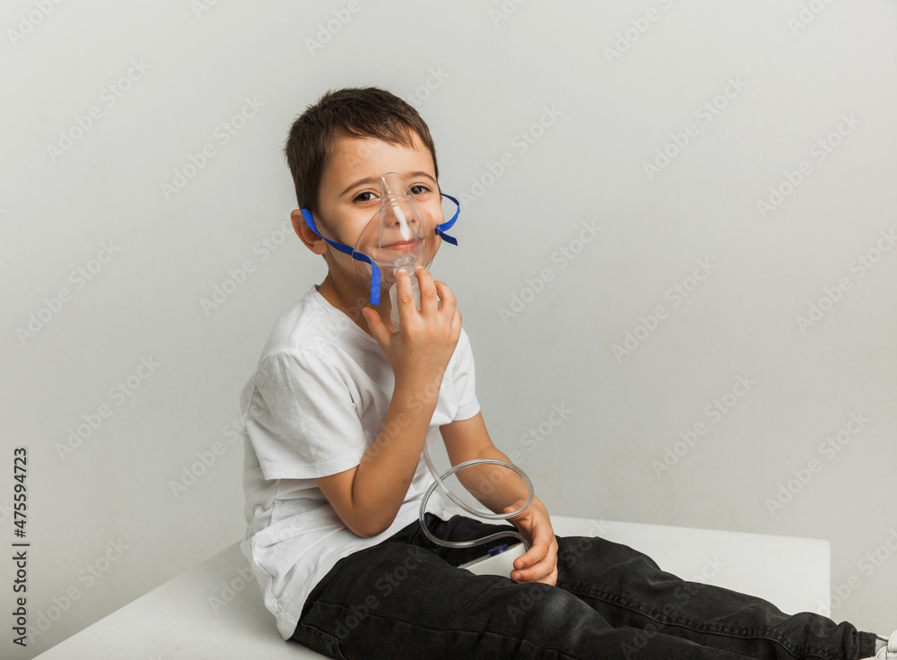 Cute little boy makes inhalation. The child holds an inhaler in his ...
