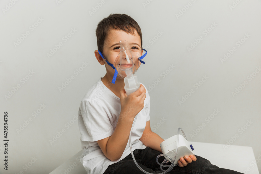 Cute little boy makes inhalation. The child holds an inhaler in his ...