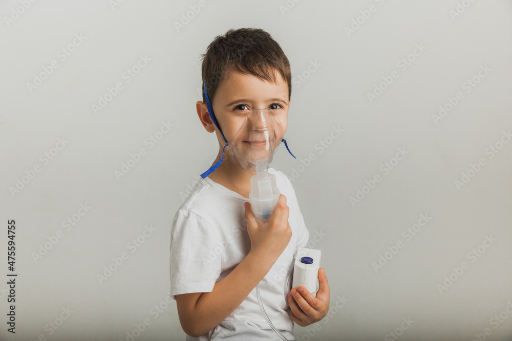 Cute little boy makes inhalation. The child holds an inhaler in his ...