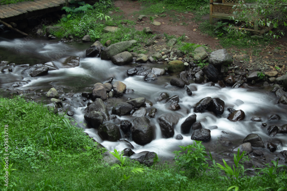 Long exposure of river water passing through rocks and grass beside the ...