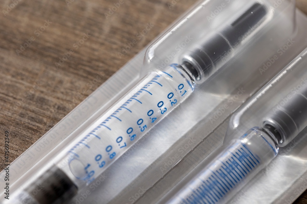A closeup portrait of a package with two syringes in it lying on a ...