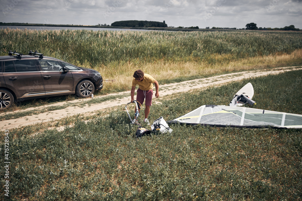 Windsurfer and camper packing and unpacking from a car's roof rack in ...