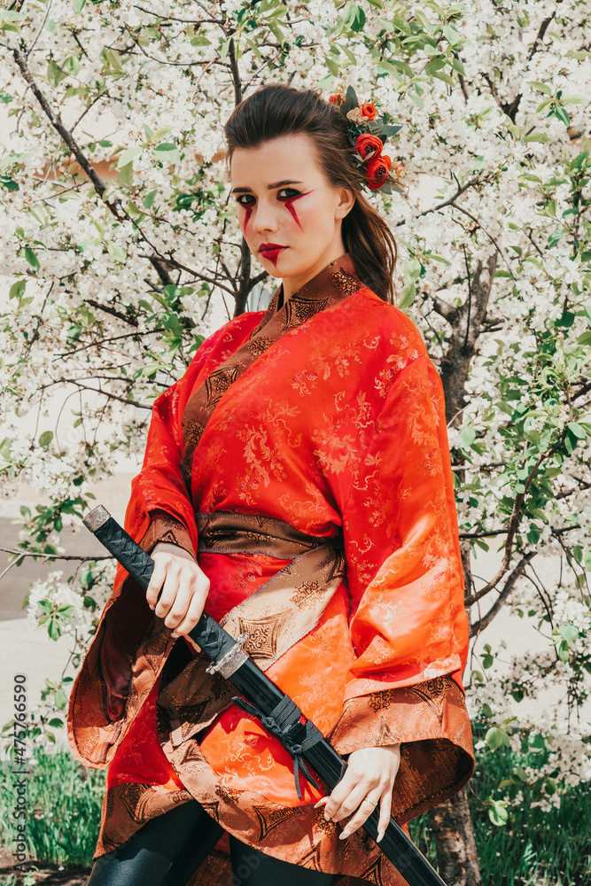 Young girl in traditional kimano in a blooming garden with samurai ...