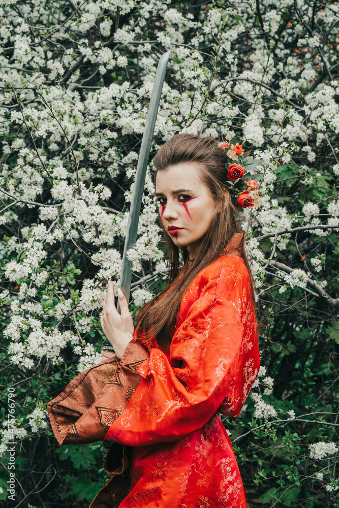 Young girl in traditional kimano in a blooming garden with samurai ...