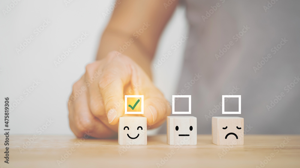 check mark over happy smiley face in wooden block with people's hand ...