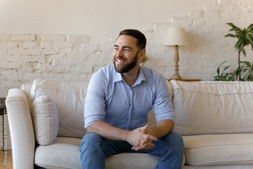 Happy dreamy millennial generation male homeowner looking in distance ...