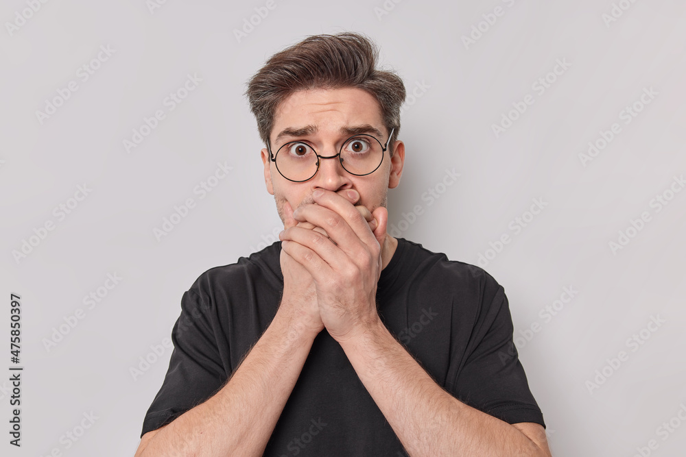 Shocked speechless young European man covers mouth with hands ties to ...