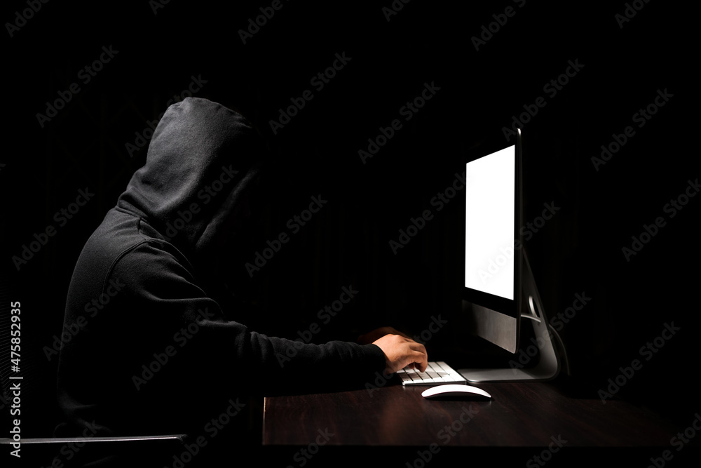 unidentified person wearing a black hoodie is sitting in front of the ...