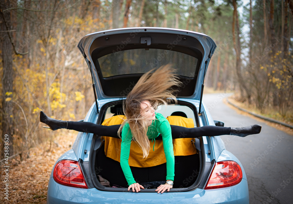 Sexy, flexible woman in the car on the road doing stretching . Concept ...