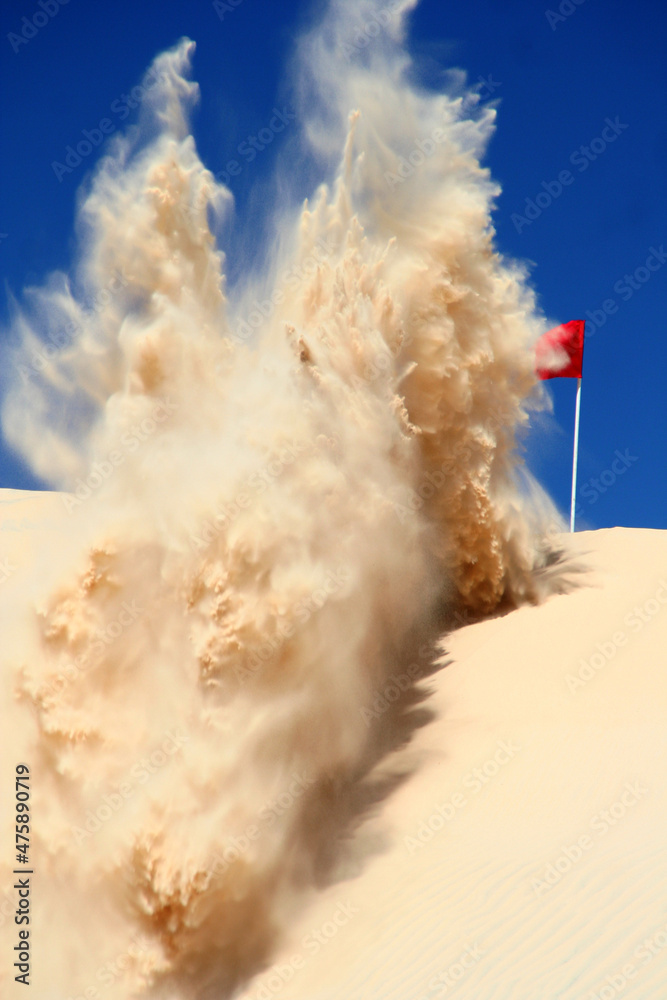 Sand explosion in the sand dunes as the sand flies up in the air ...