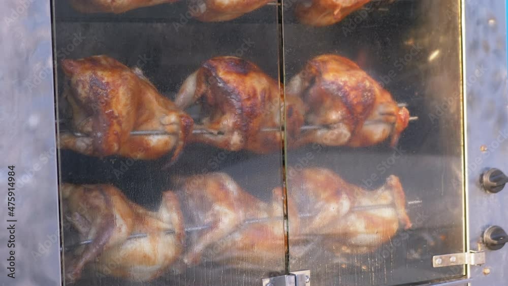 Grilled Chickens Rotates on a Barbecue Grill Skewer in a Closed oven ...