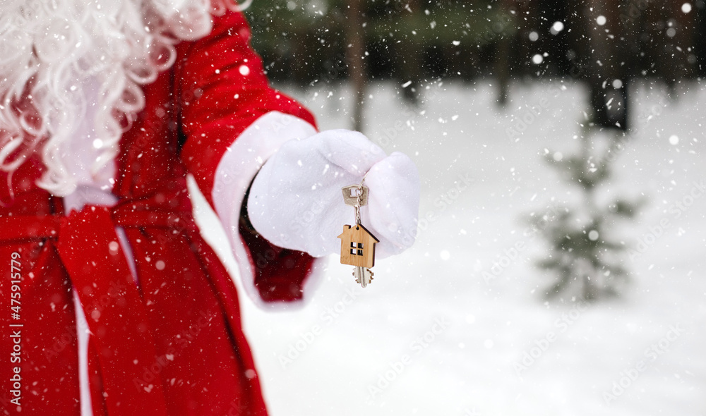 House key with keychain cottage in hands of Santa Claus outdoor in snow ...