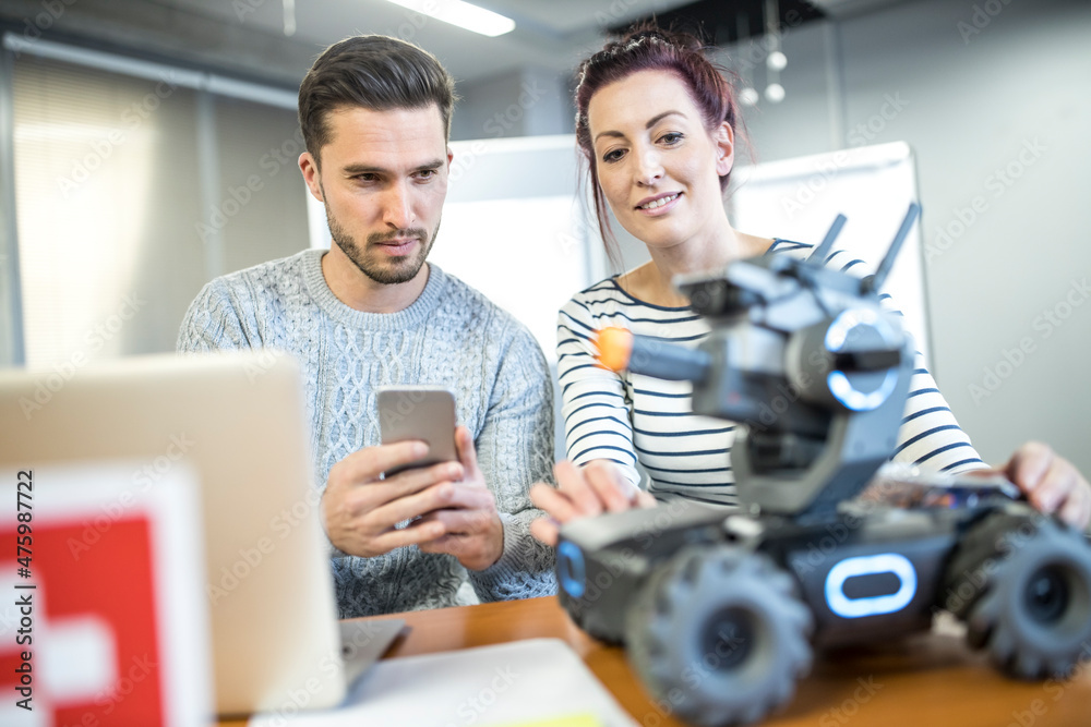 Engineer checking robotic combat tank with colleague at workshop Stock ...