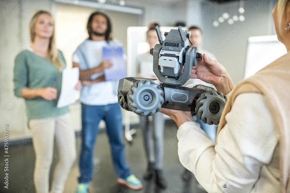 Developer introducing robotic combat tank model to team at workshop ...