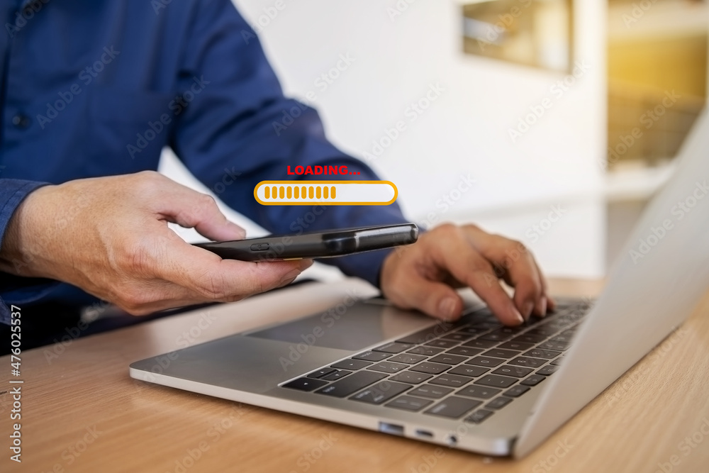 Businessman using mobile phone loading data with a computer for backup ...