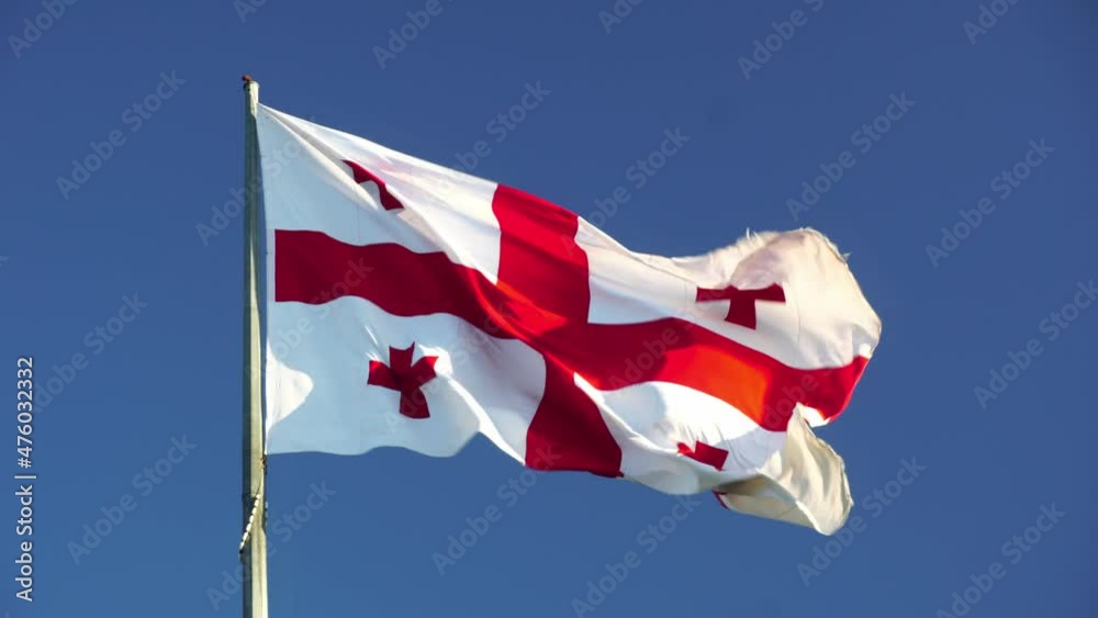 The Georgian flag is flying against the blue sky. The symbol of the ...