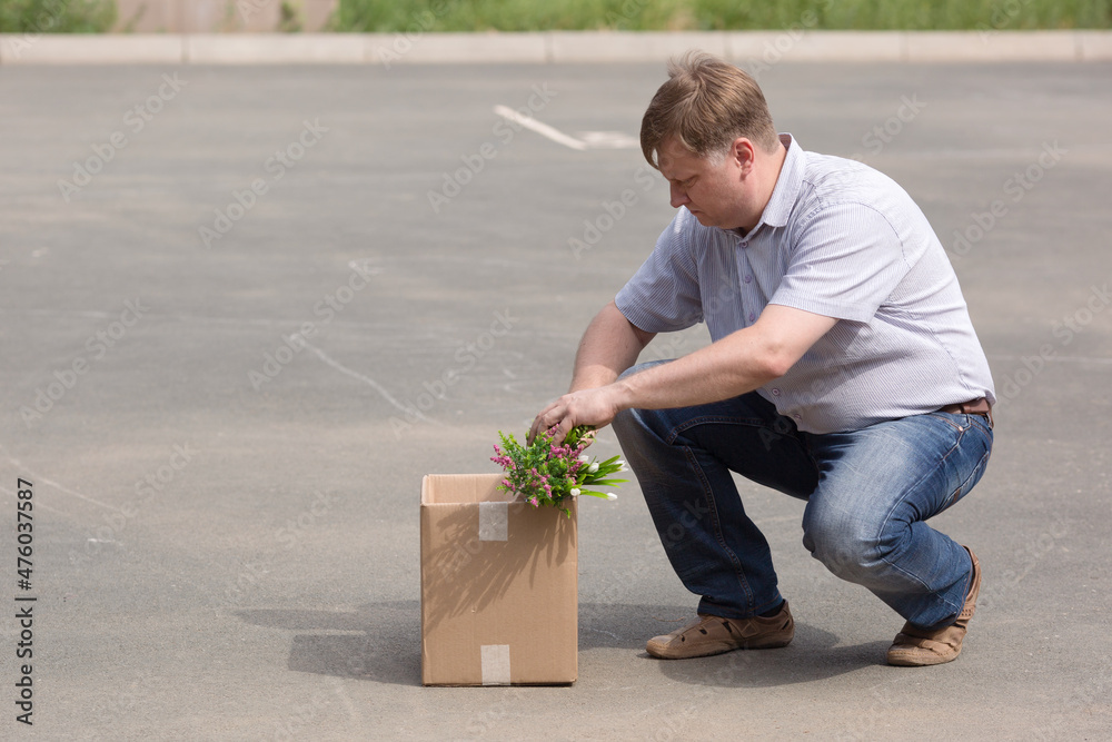 Upset man lays out his personal belongings in a box on the street, the ...