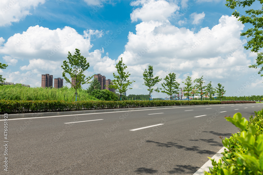 Clear sky, white clouds, asphalt roads and roadside trees on both sides ...