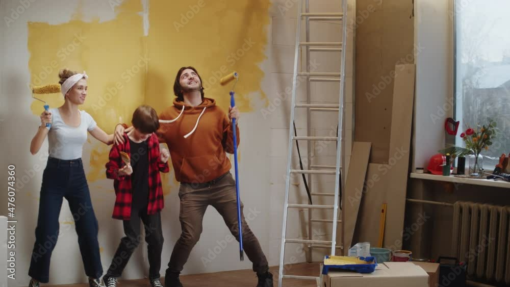 Family painting walls in yellow and dancing, making overhaul together ...