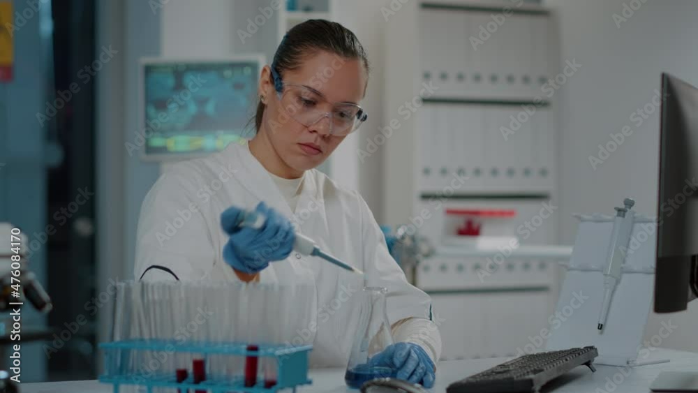 Lab worker using micro pipette with beaker and test tubes to do ...