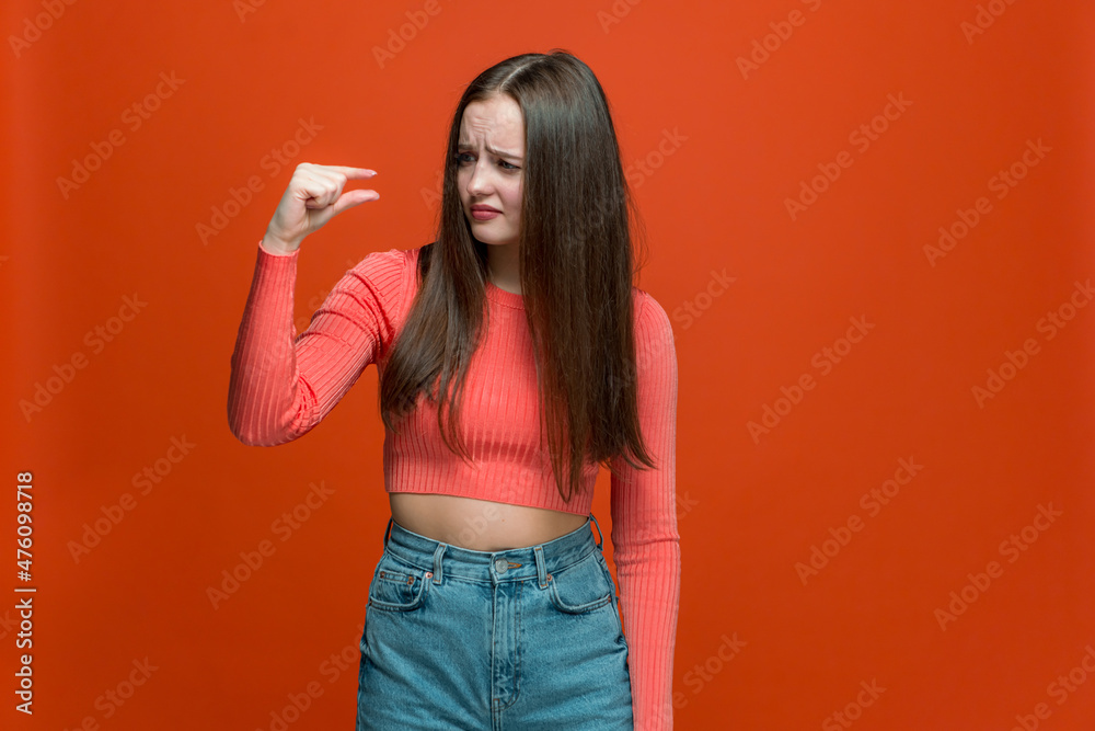 Foto de Displeased young girl making a little bit gesture, small size ...