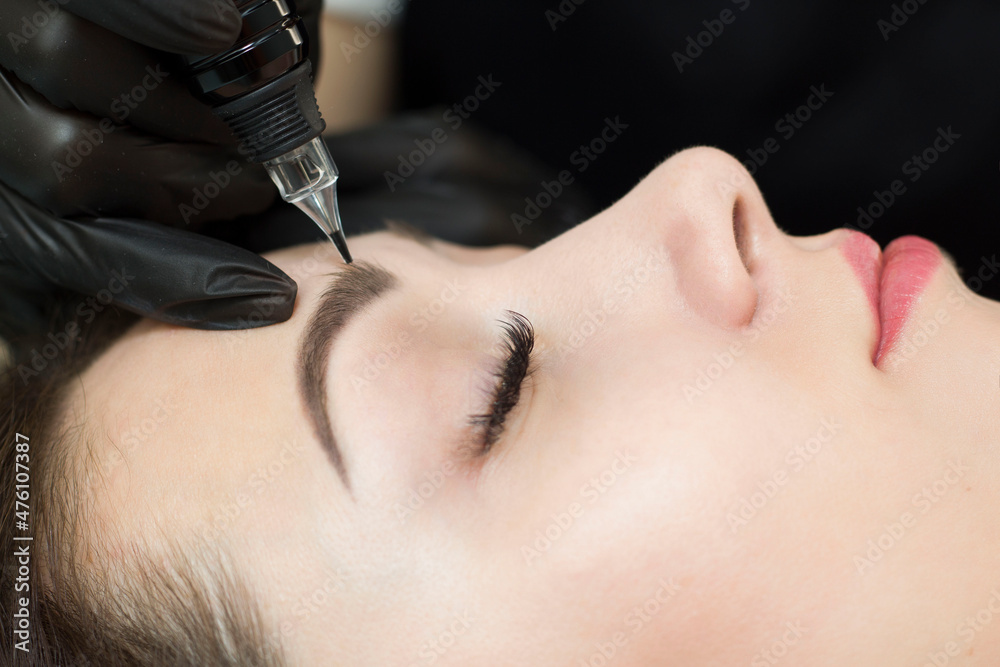 Permanent makeup. Permanent eyebrow tattoo. Cosmetologist applying ...