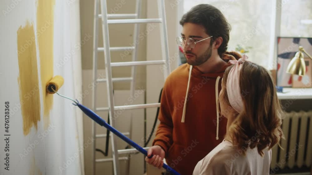 Young couple man and woman painting walls in yellow and quarreling ...