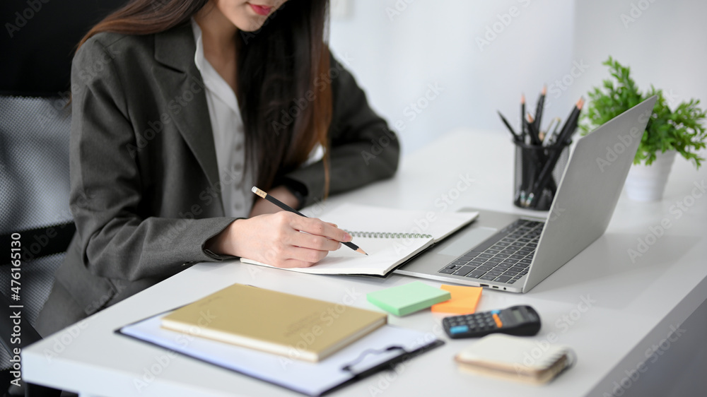Businesswoman working at her office desk, writing on her personal book ...