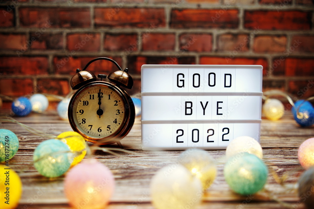 Goodbye 2022 text in light box with alarm clock and LED cotton balls ...