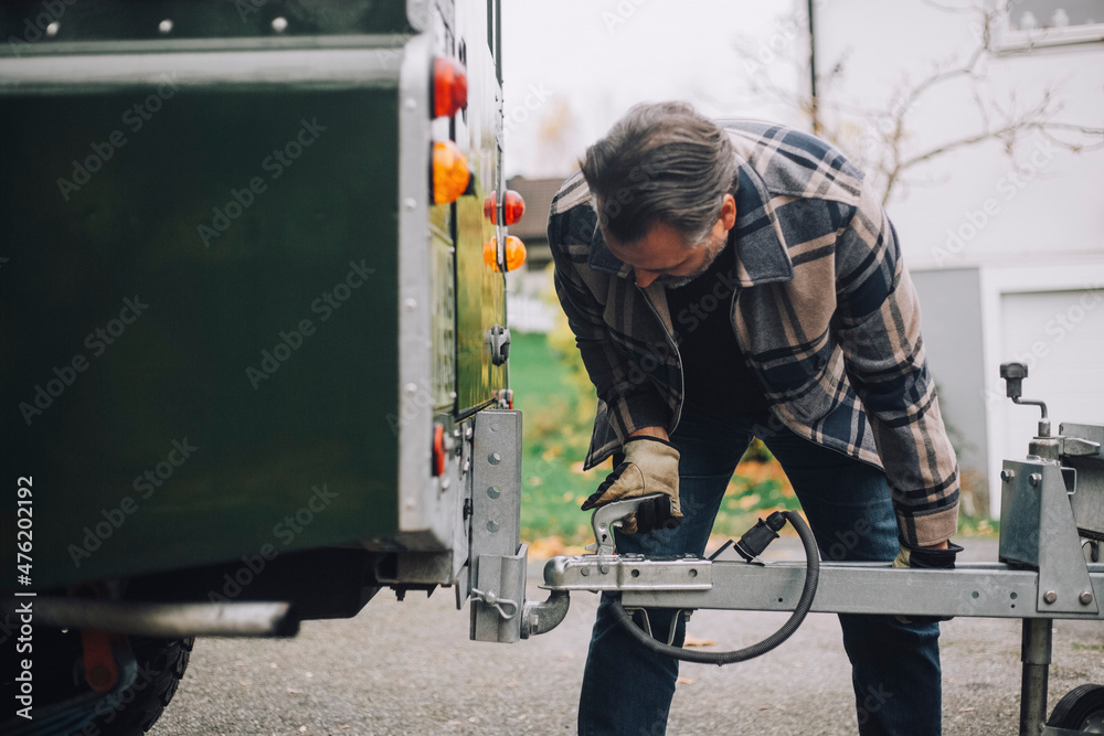 Mature man towing trailer to sports utility vehicle on driveway Stock ...