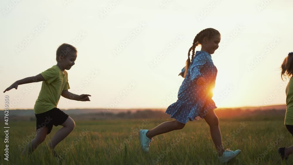 Happy children run on green grass at sunset. Family play with ball in ...