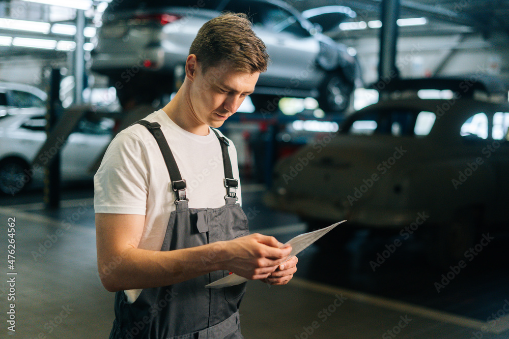 Side view of focused handsome young mechanic male wearing uniform ...
