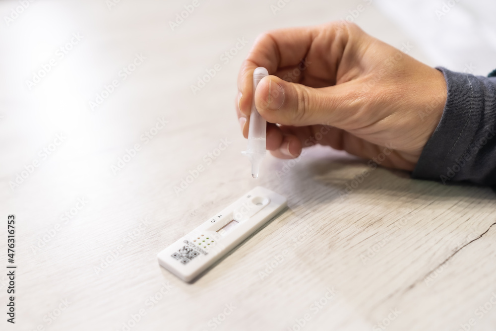 Applying the liquid to the test. A young woman doing the rapid antigen ...