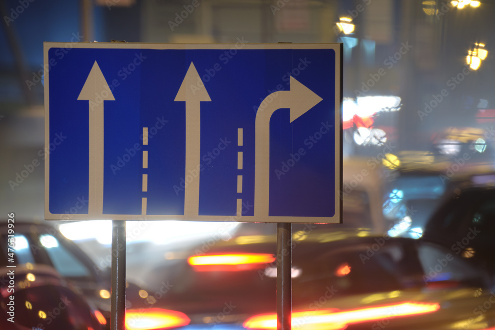 Direction road signs with blurred cars on city street traffic at night ...