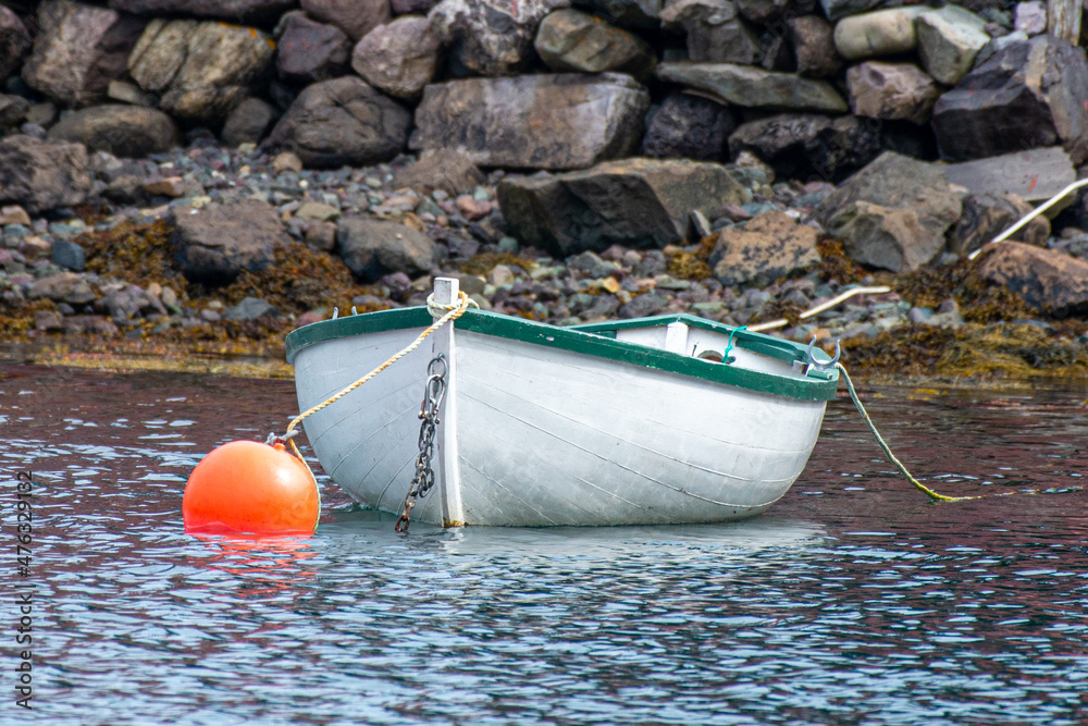 A white wooden traditional dory or small fishing vessel with green trim ...