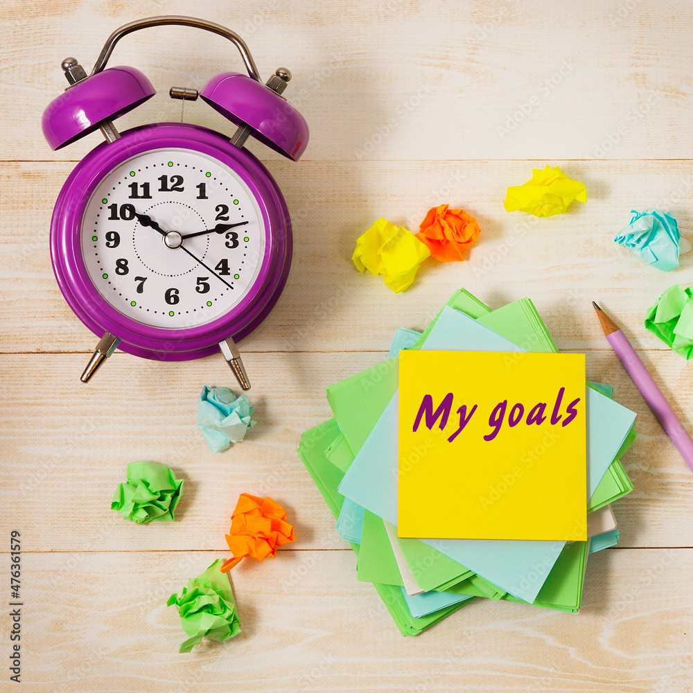 Top view of a table with a clock, a stack of scrapbook paper and ...