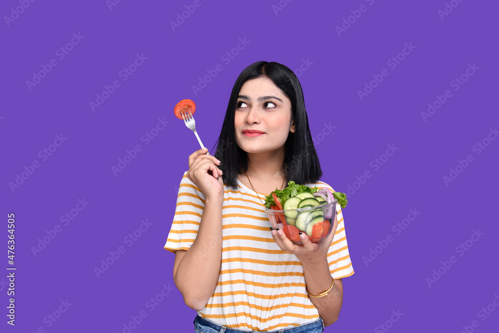 foodie girl holding vegetable salad bowl over purple background indain ...