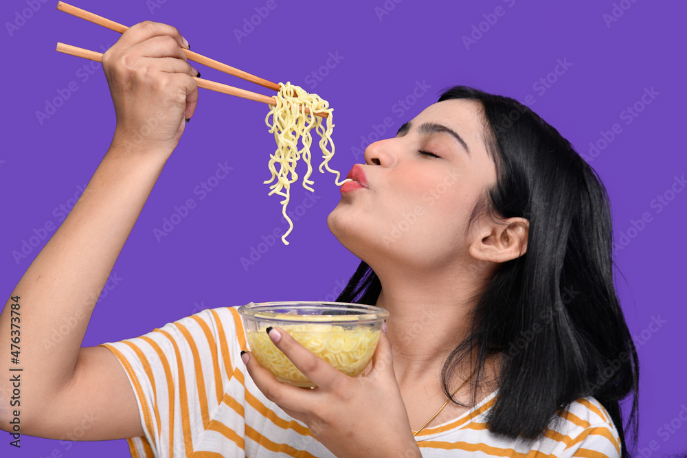 foodie girl eating noodle over purple background indian pakistani model ...