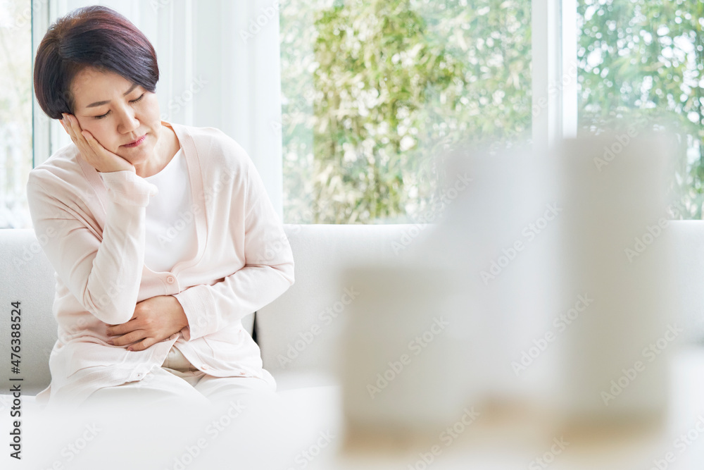 Middle-aged woman suffering from stomatitis on the sofa in the living ...