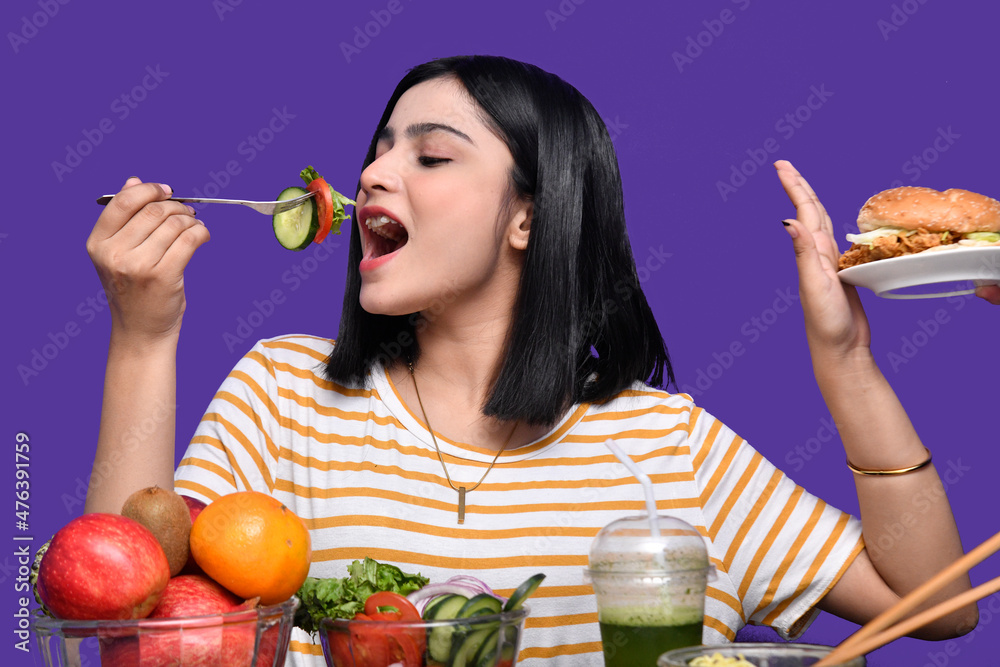 foodie girl sitting at fruit table eating salad and open hand stop sign ...
