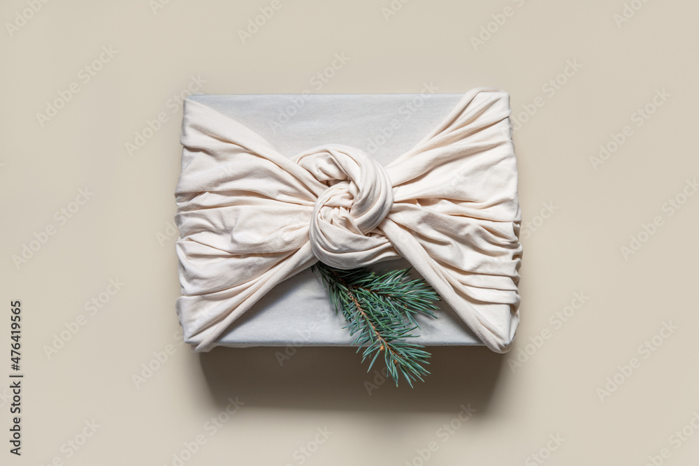 Christmas present in beige cotton fabric with spruce twigs. Traditional ...