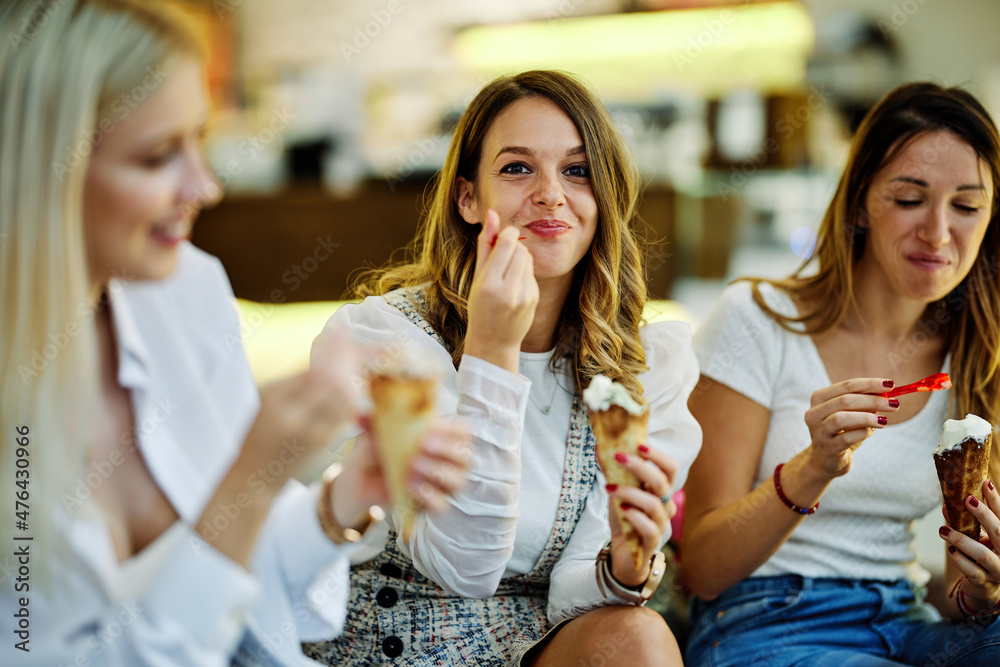Three girls sitting in cafe and eating ice cream. Stock Photo | Adobe Stock