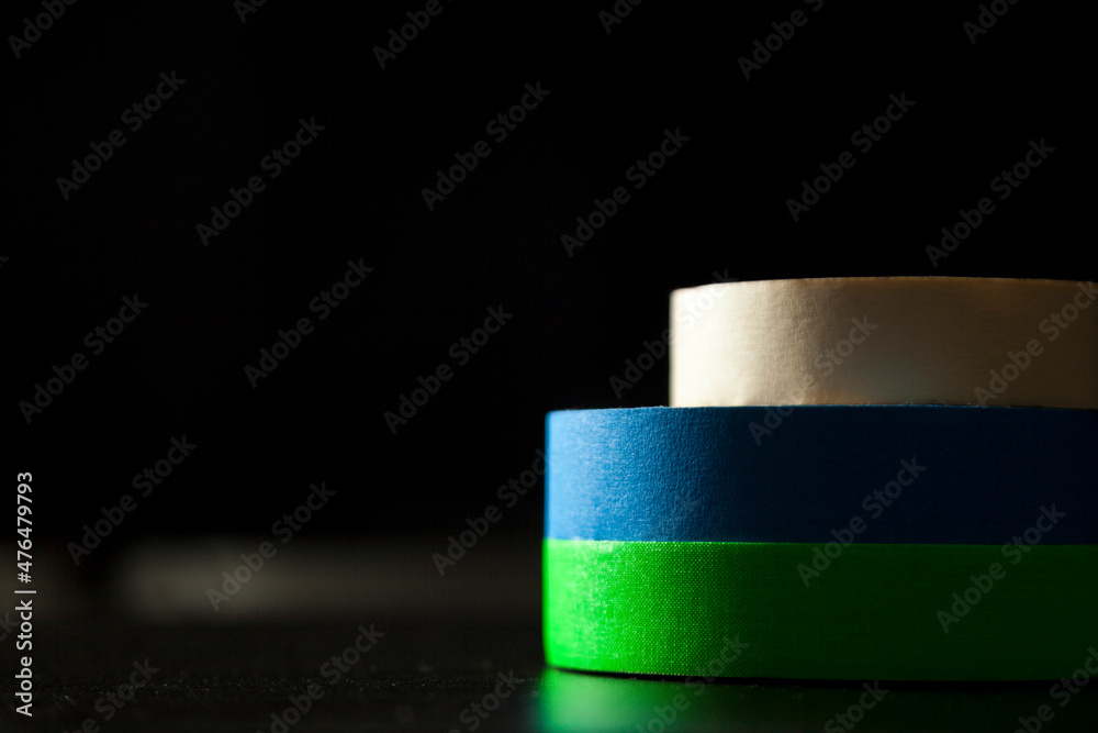Colored adhesive tapes stacked on a table and black background. With ...